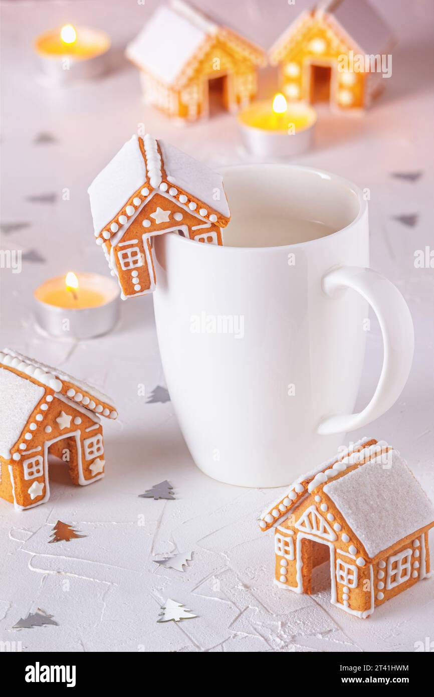 Gingerbread huts and a cup of milk on a white textured surface with ...