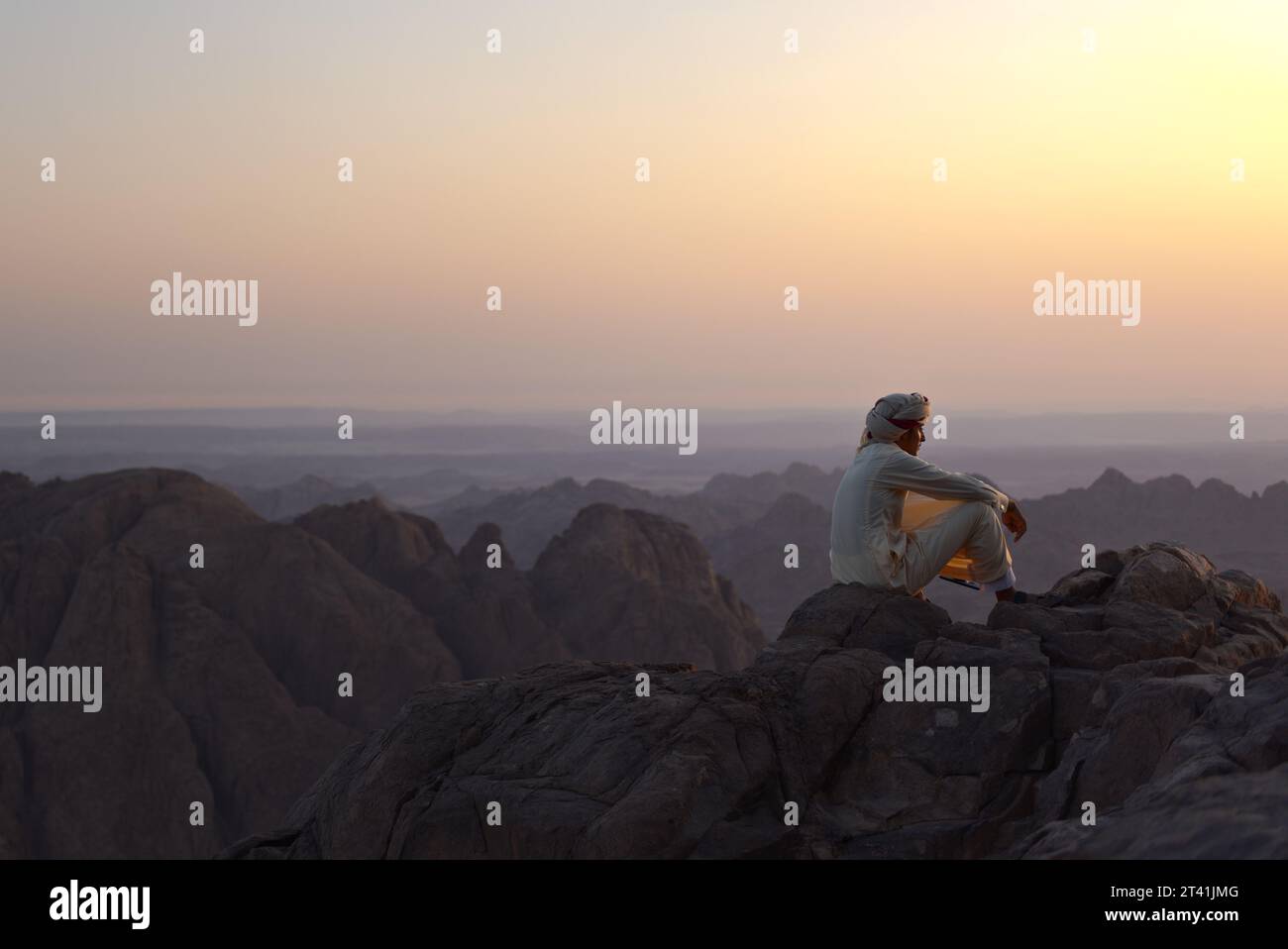 Young man, sitting alone, admiring the sunrise. The scene takes place ...