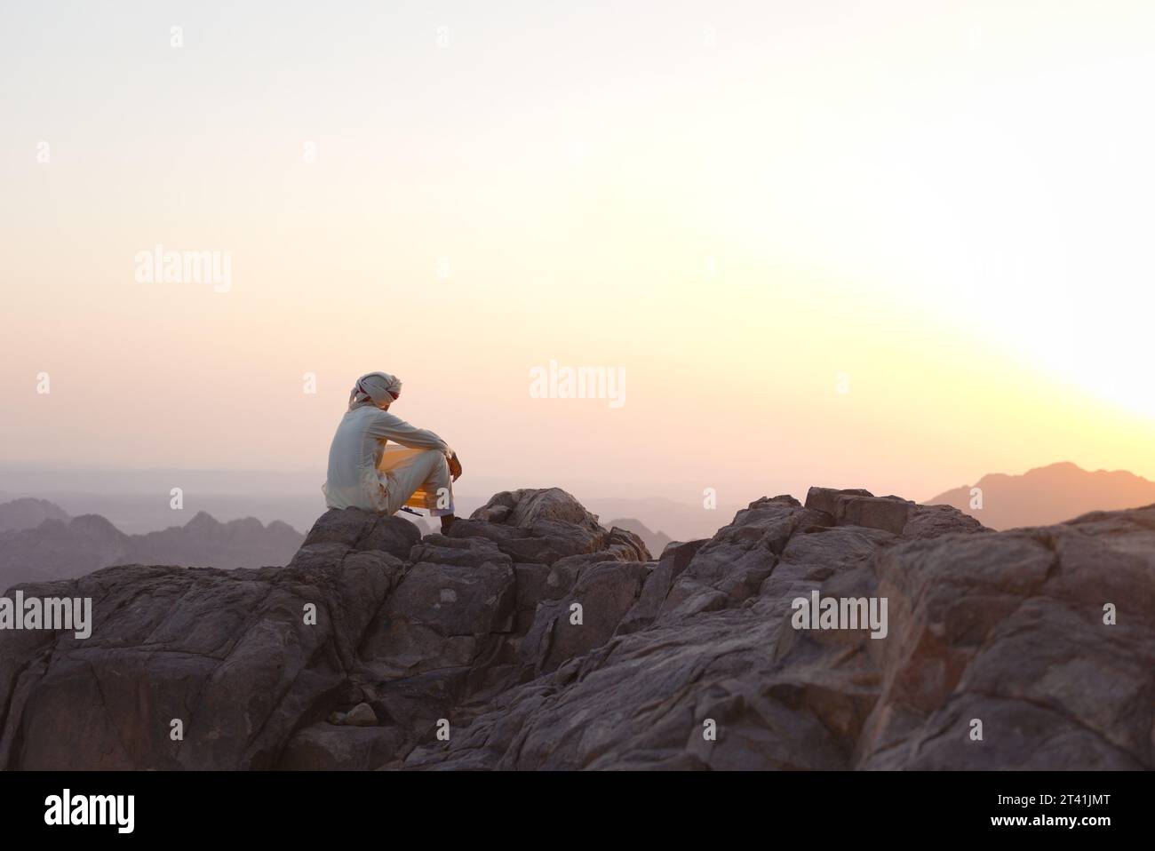 Young man, sitting alone, admiring the sunrise. The scene takes place ...