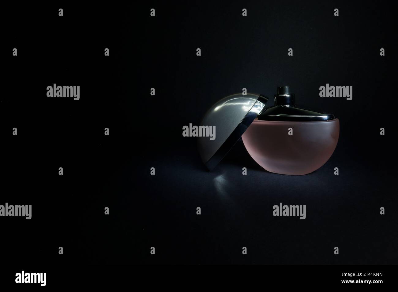 A women's perfume in a nice pink glass bottle on a black background ...