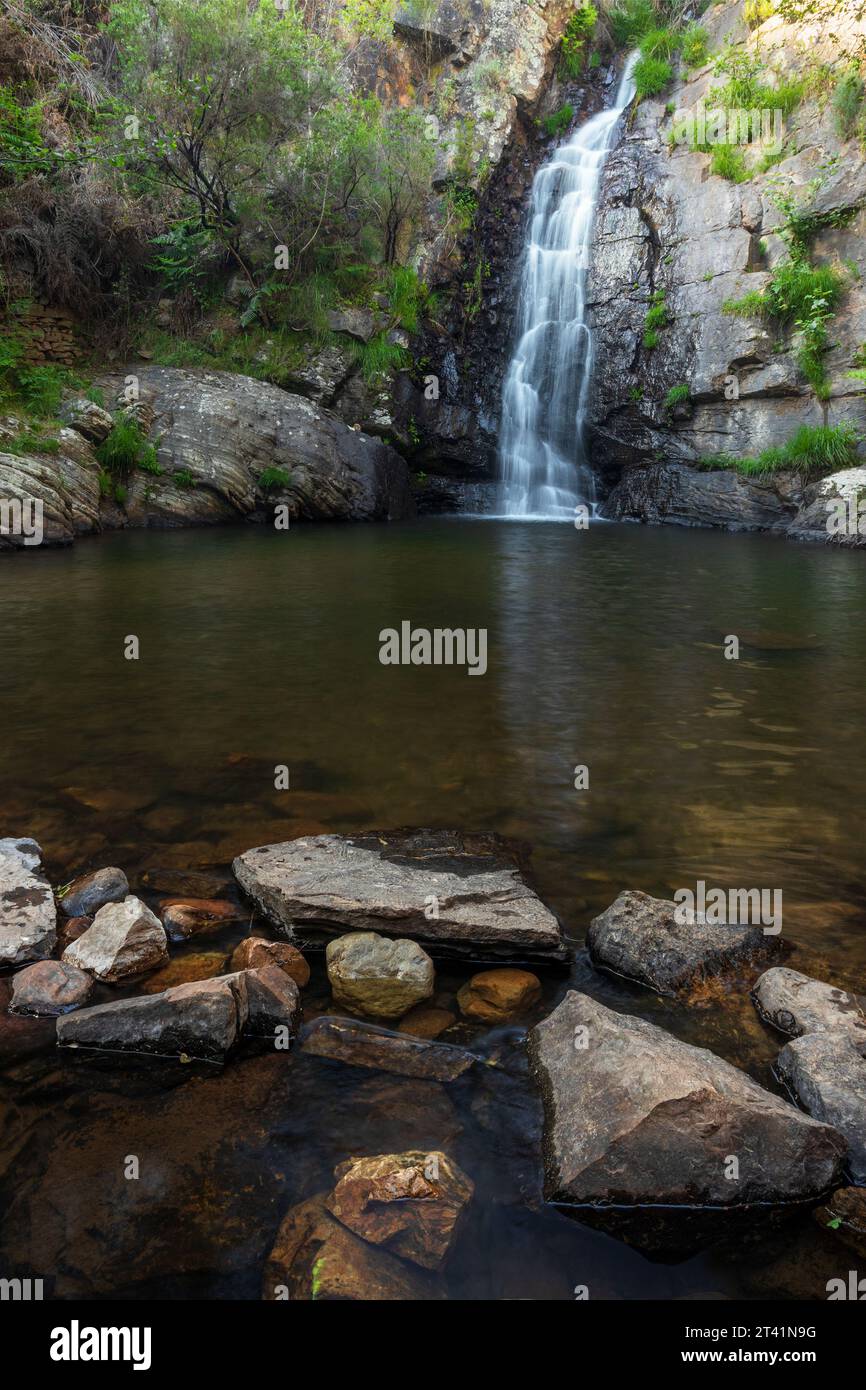 Idyllic lake landscape with a waterfall and rocks in the foreground at ...