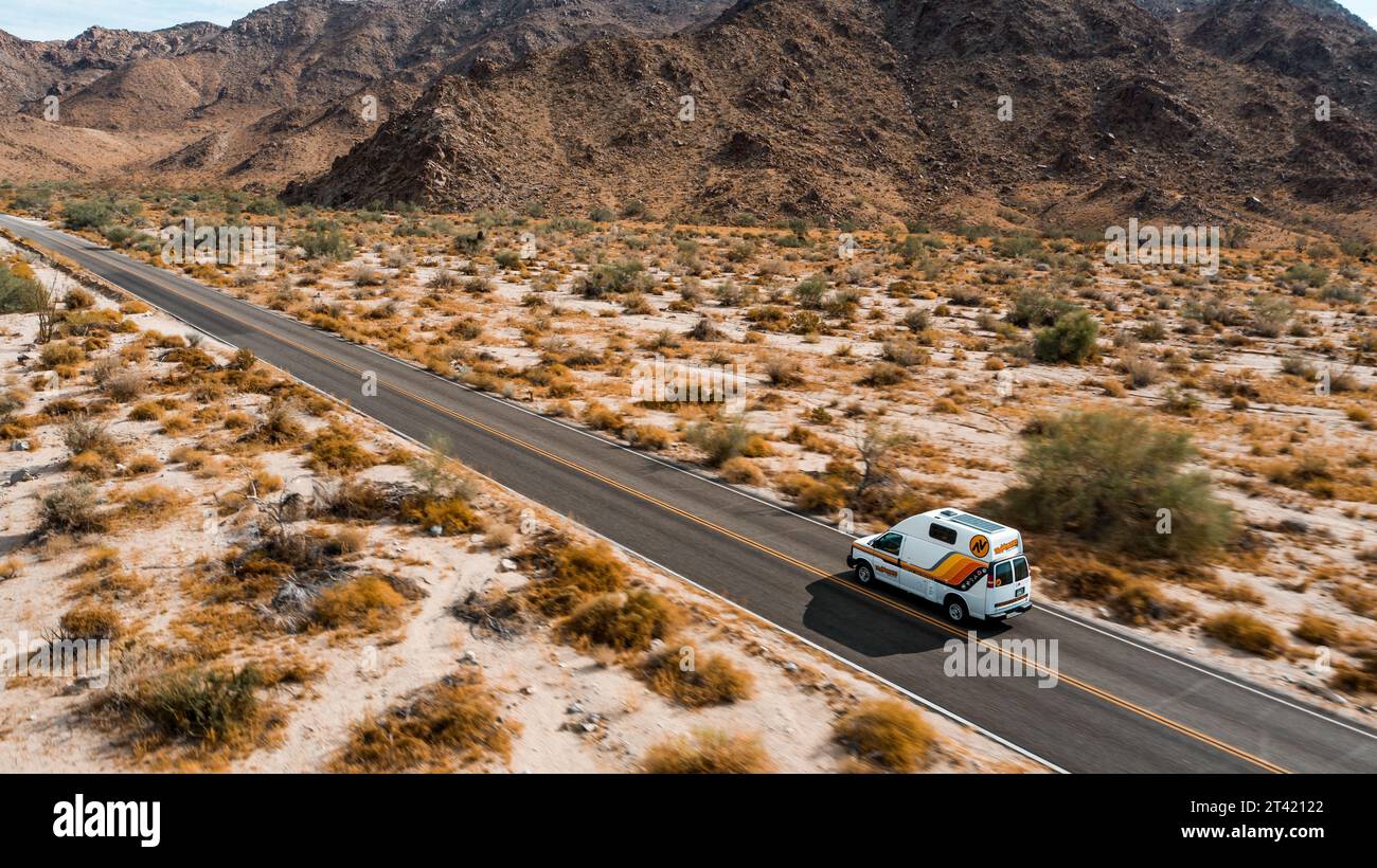 An aerial view of a camping van driving along a desert landscape in ...