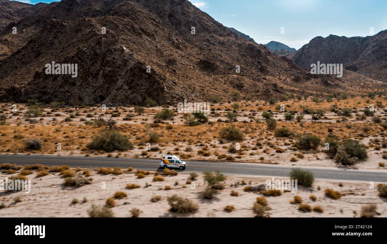 An aerial view of a camping van driving along a desert landscape in ...
