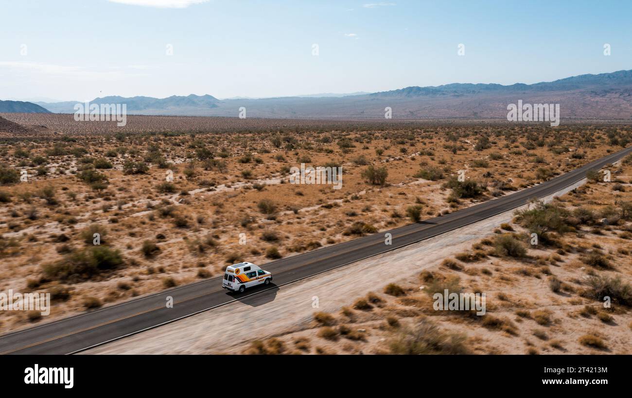 An aerial view of a camping van driving along a desert landscape in ...