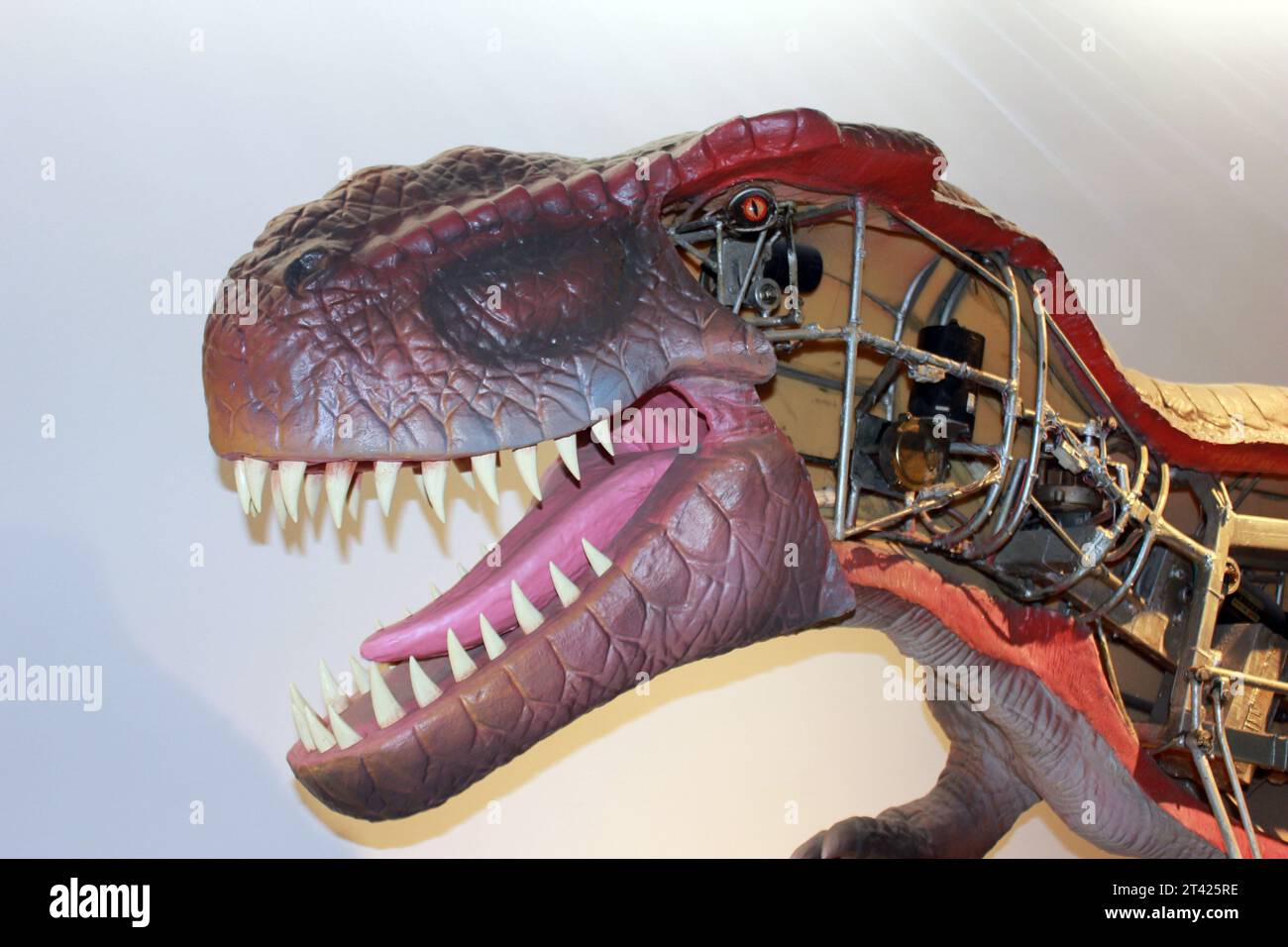 A metallic robotic dinosaur stands in a pose with its mouth open ...