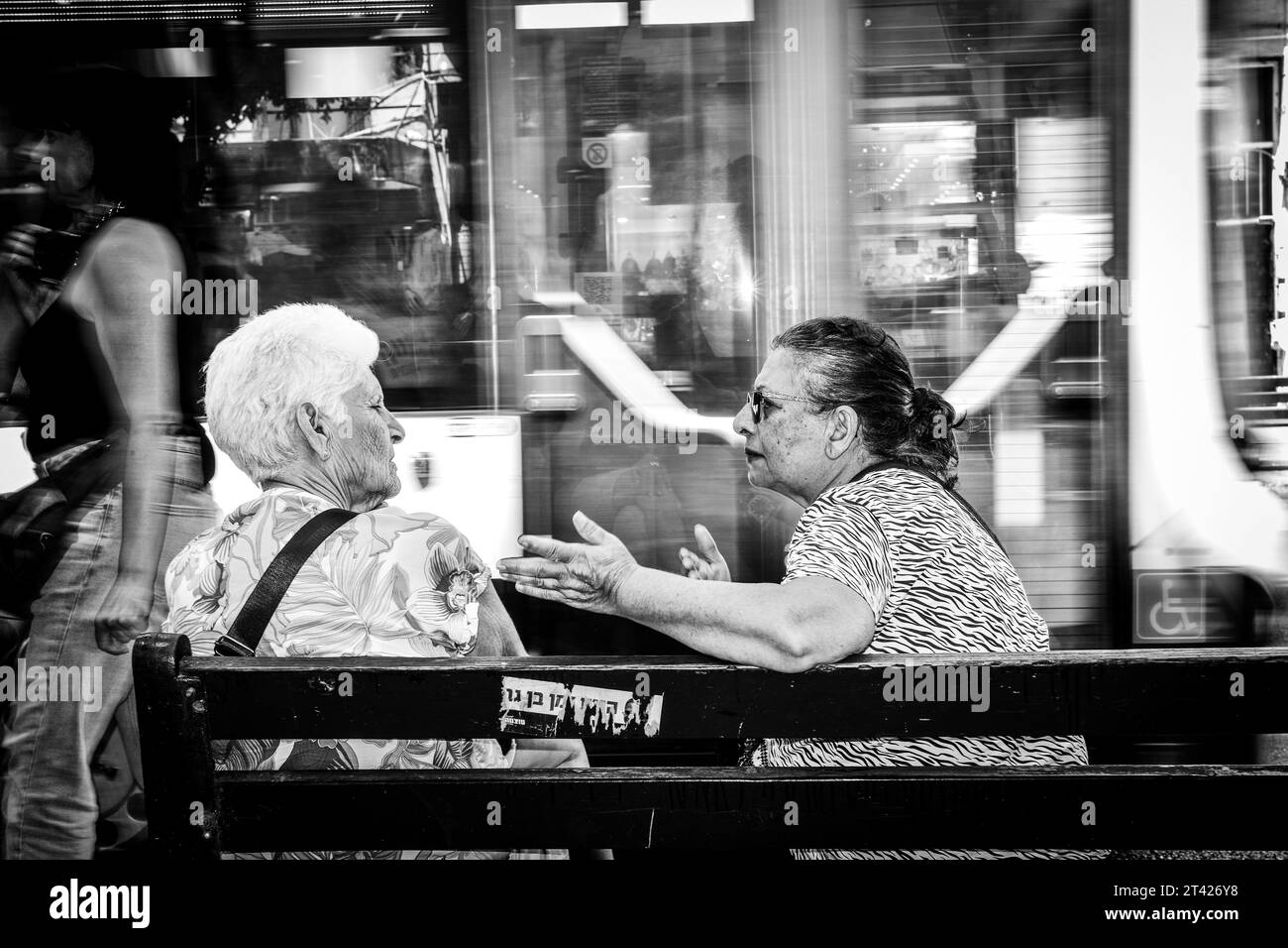 A black and white shot of two elderly females sitting side-by-side on a ...