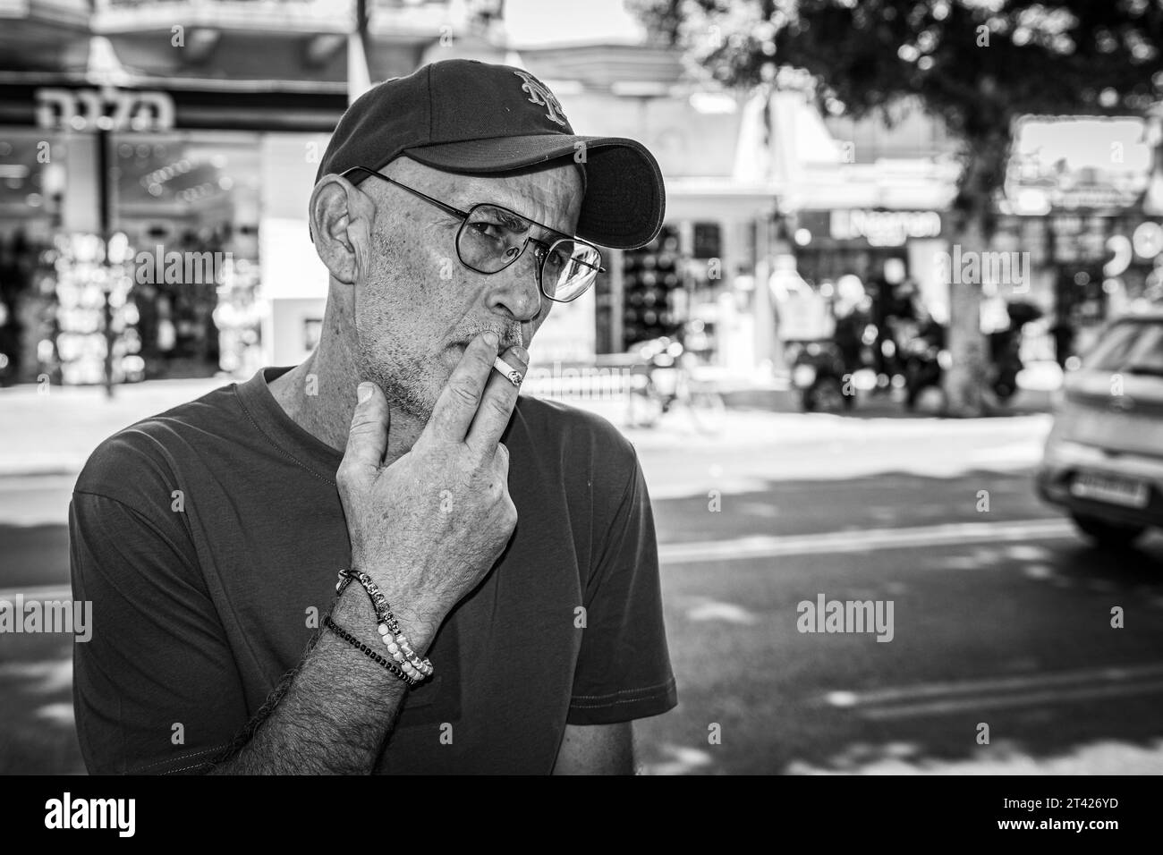 A mature man smoking a cigarette while standing by the side of a road ...