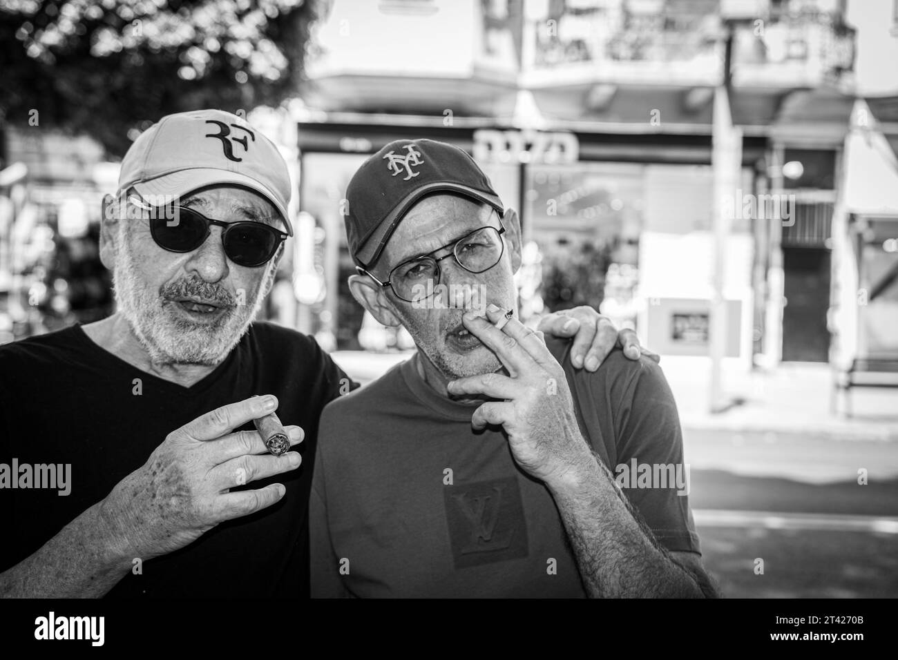 The two older people standing near each other and smoking a cigarette ...