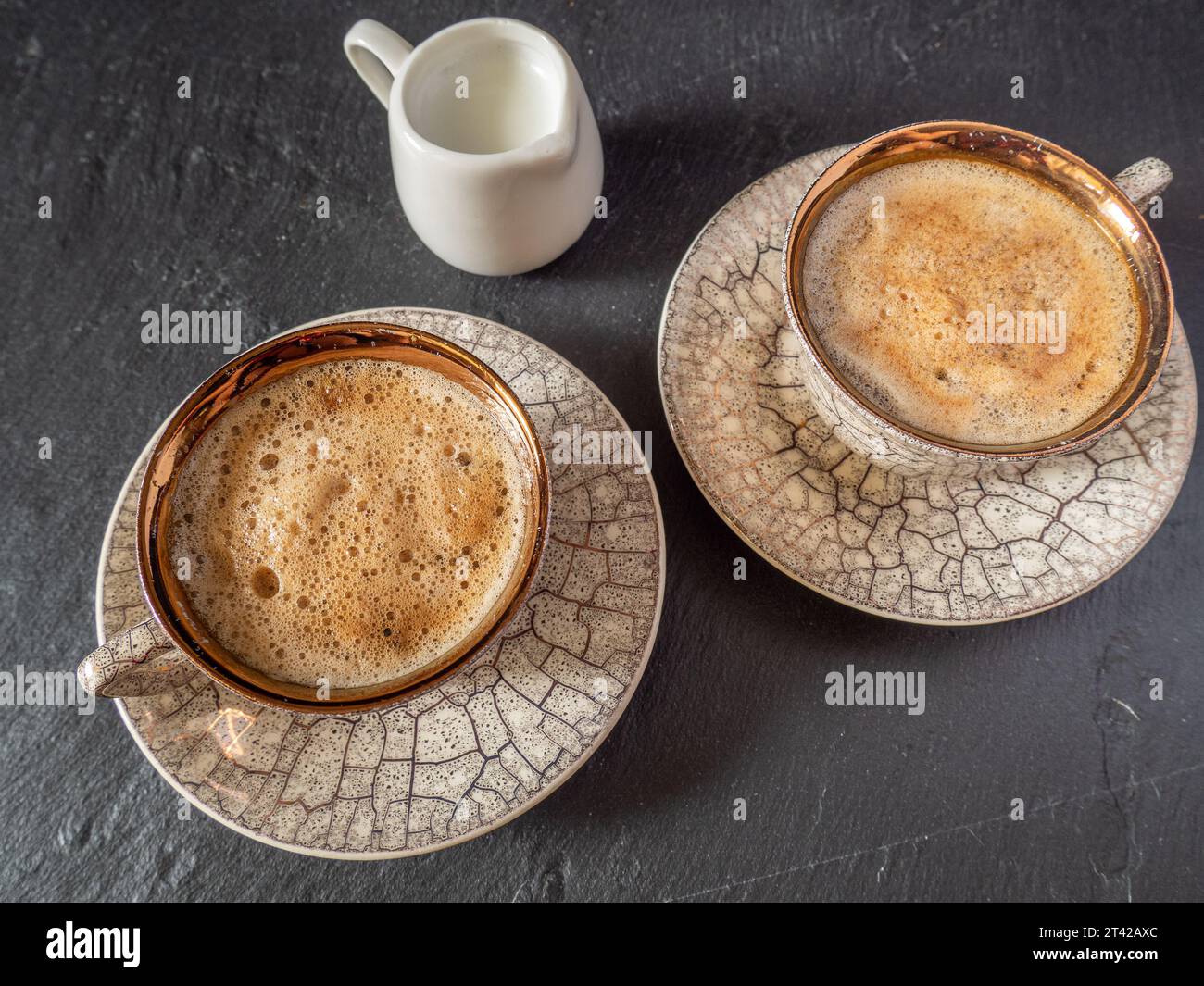 A set of two cups of cappuccinos on a light gray, table Stock Photo - Alamy