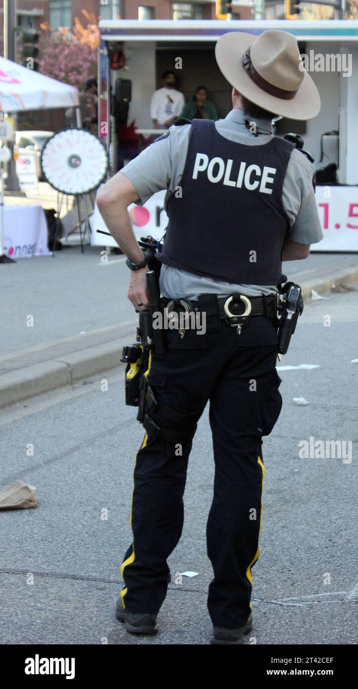 A uniformed police officer is standing in the street, looking intently ...