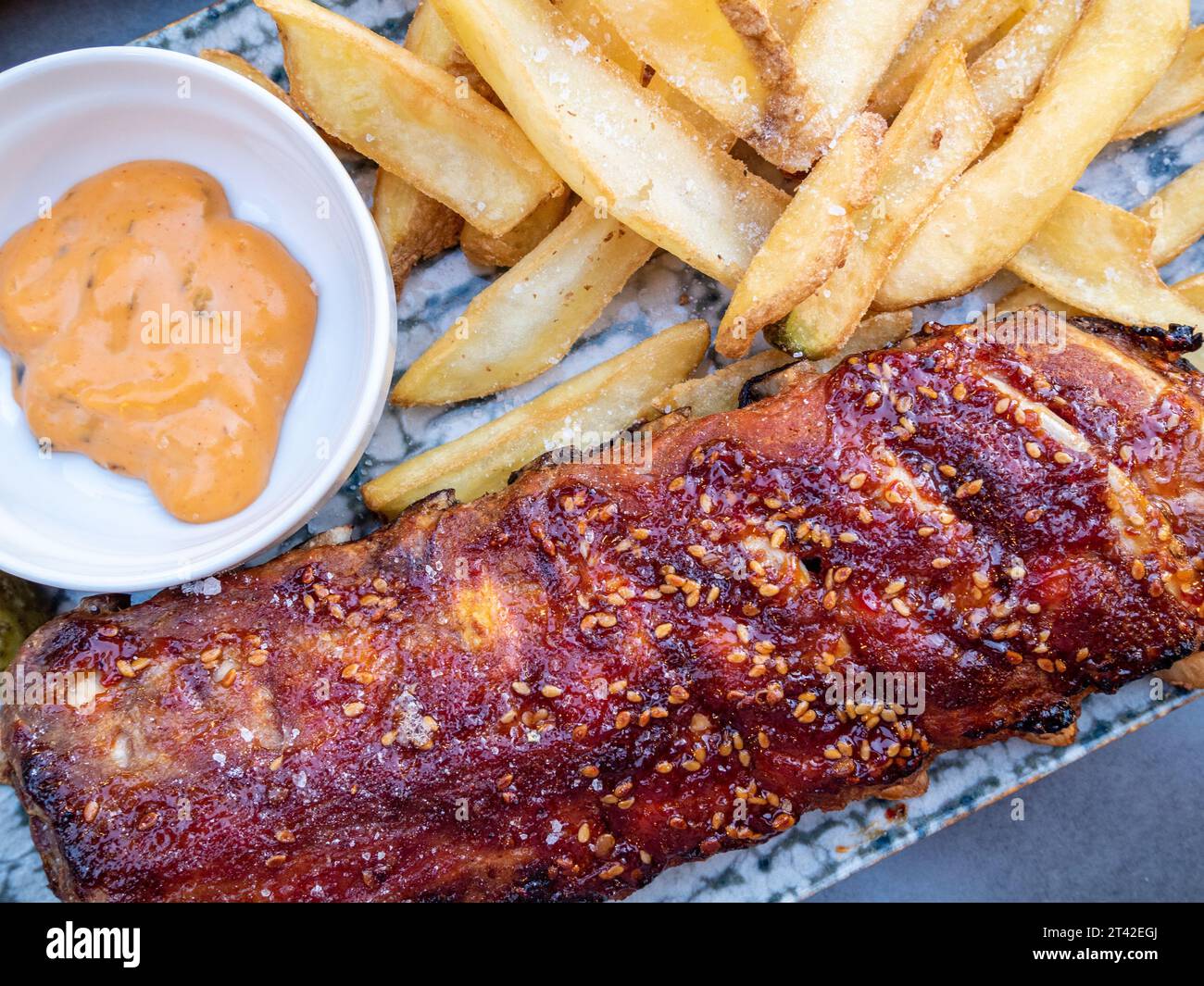 A plate with a portion of freshly-cooked French fries, with a barbeque ...