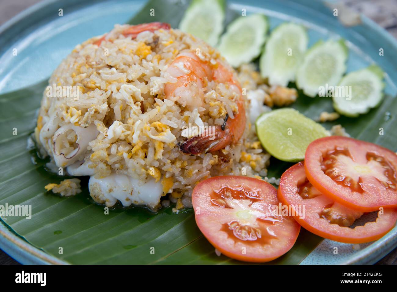 Shrimp and squid fried rice with sliced tomatoes and cucumbers on ...