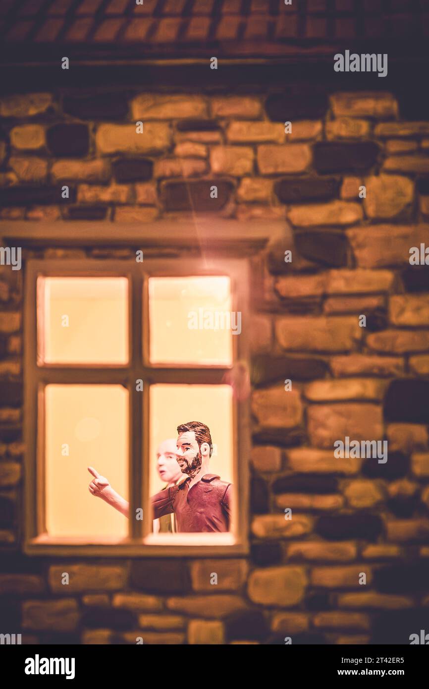 A silhouetted man stands in a window of a stone building, gazing out ...