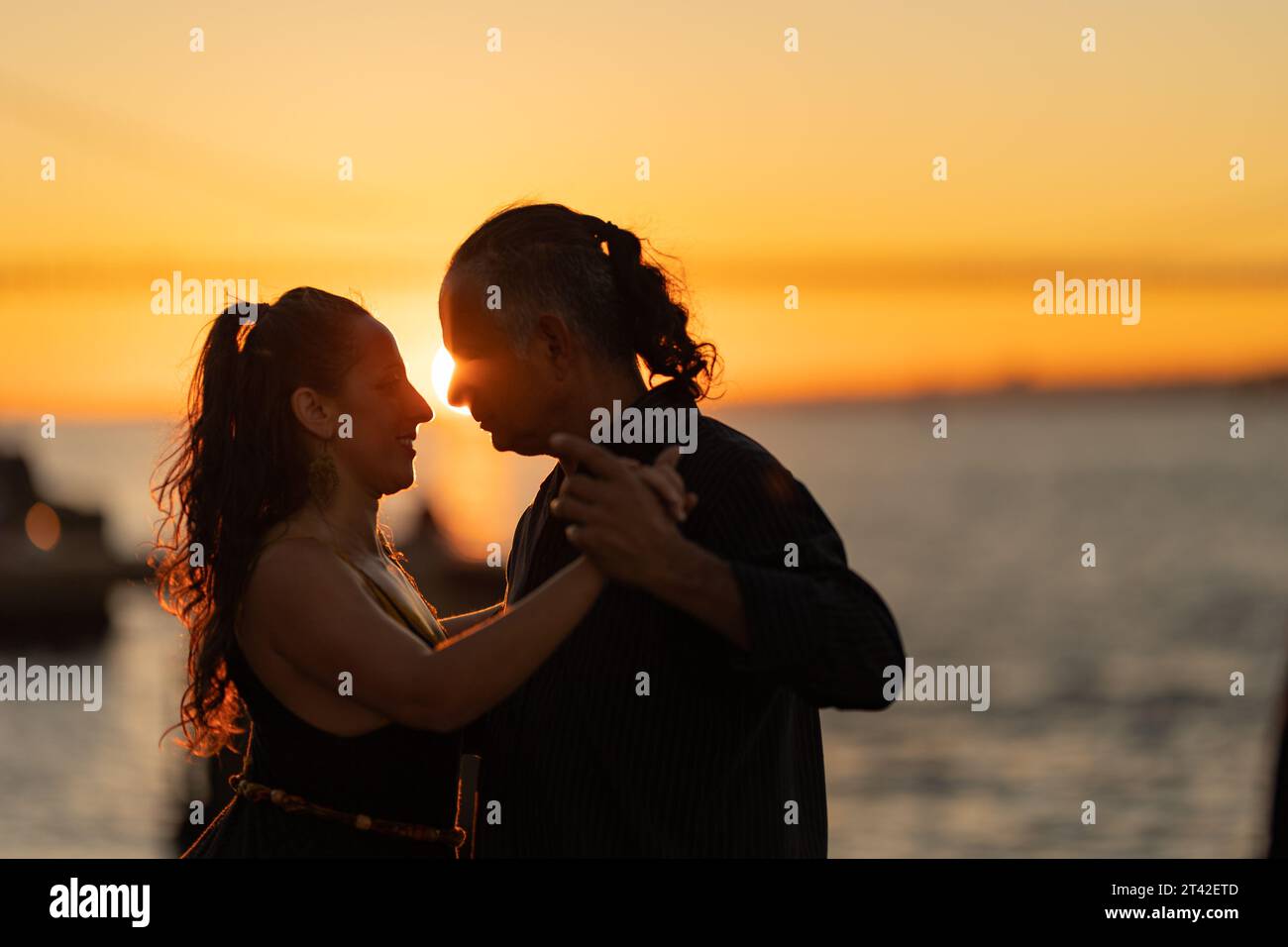 Close-up of couple embracing at sunset - dancing near river bridge ...