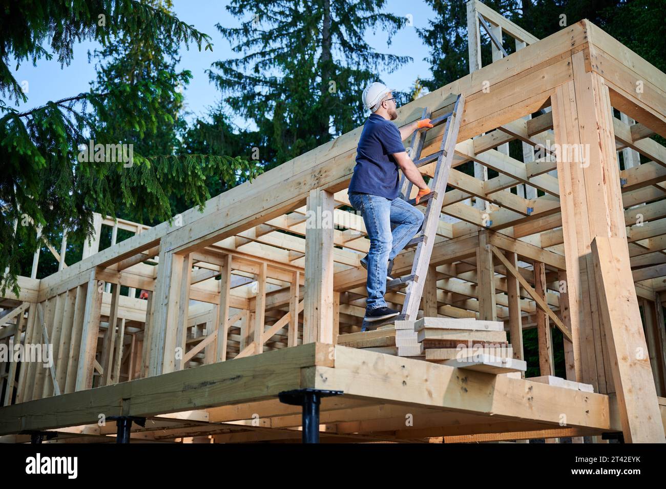 Carpenter constructing wooden frame house near the forest. Bearded man ...