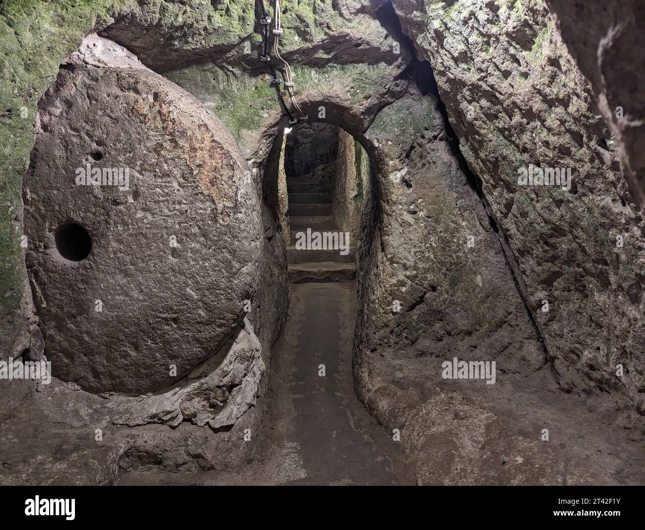 An underground tunnel with two large stone statues on the right side ...