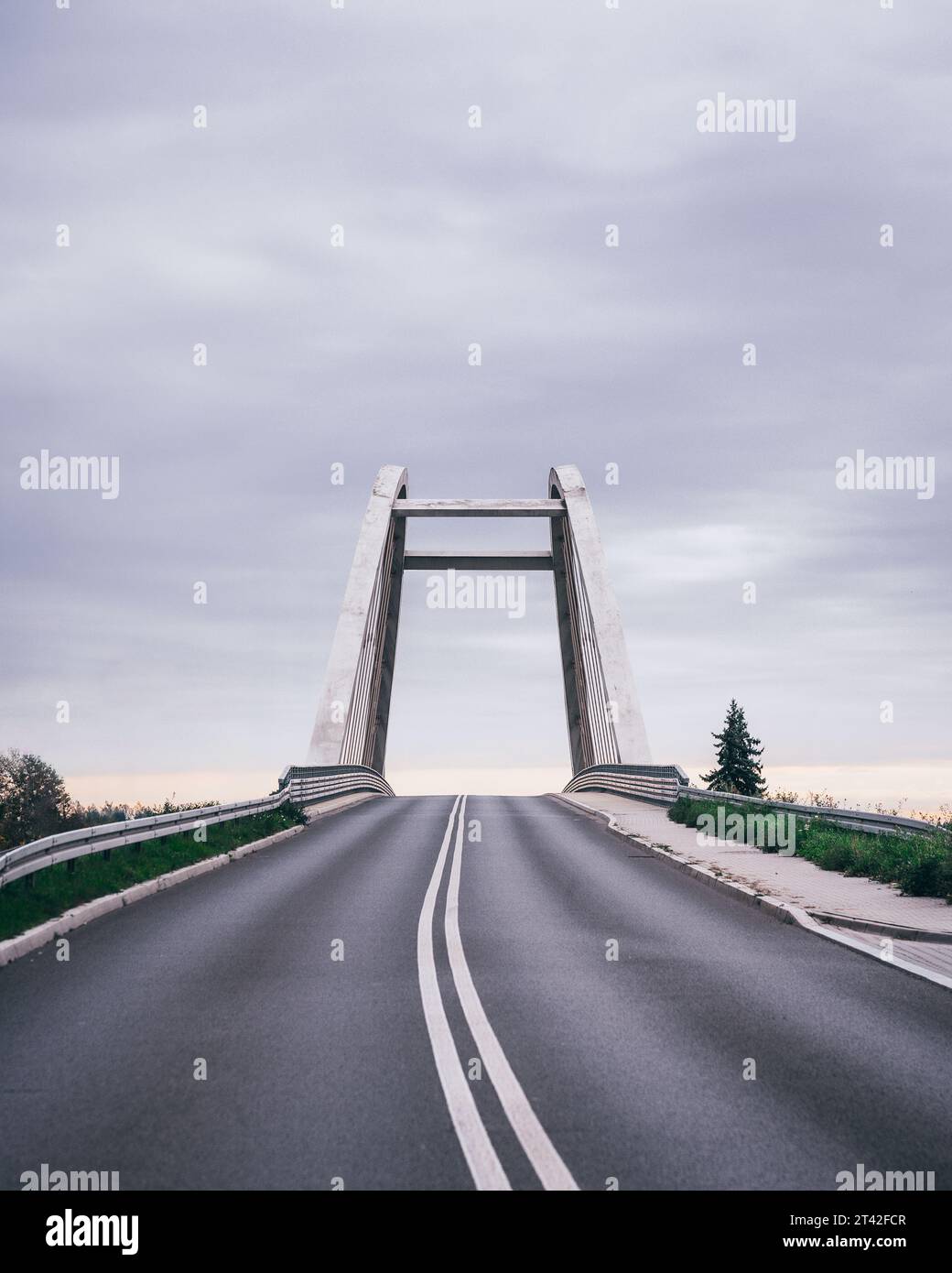 A two-lane road going through an expansive bridge, with a clear blue ...