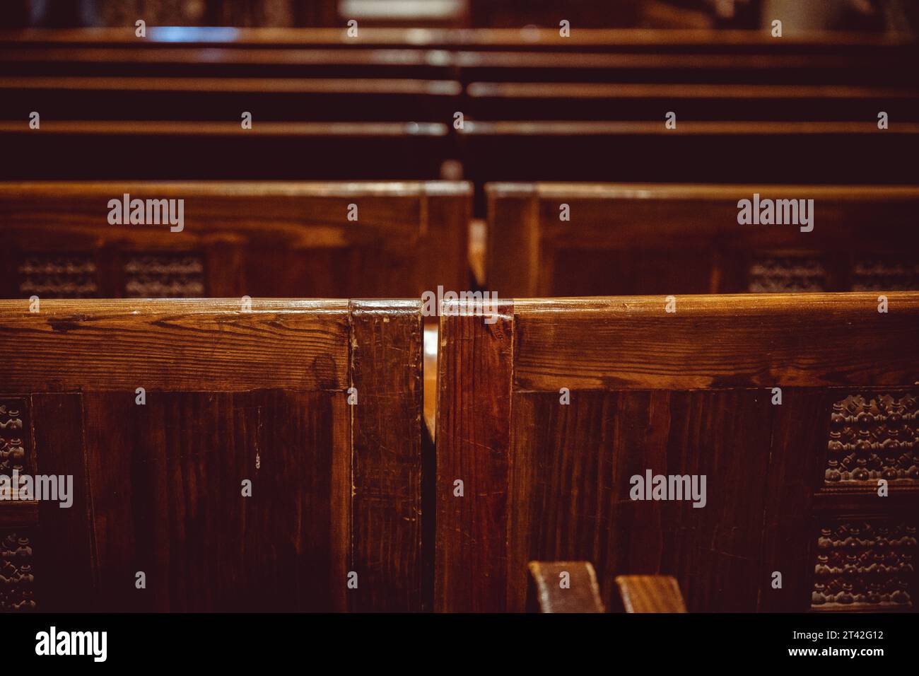 A traditional wooden church pew with a sunbeam shining through the back ...