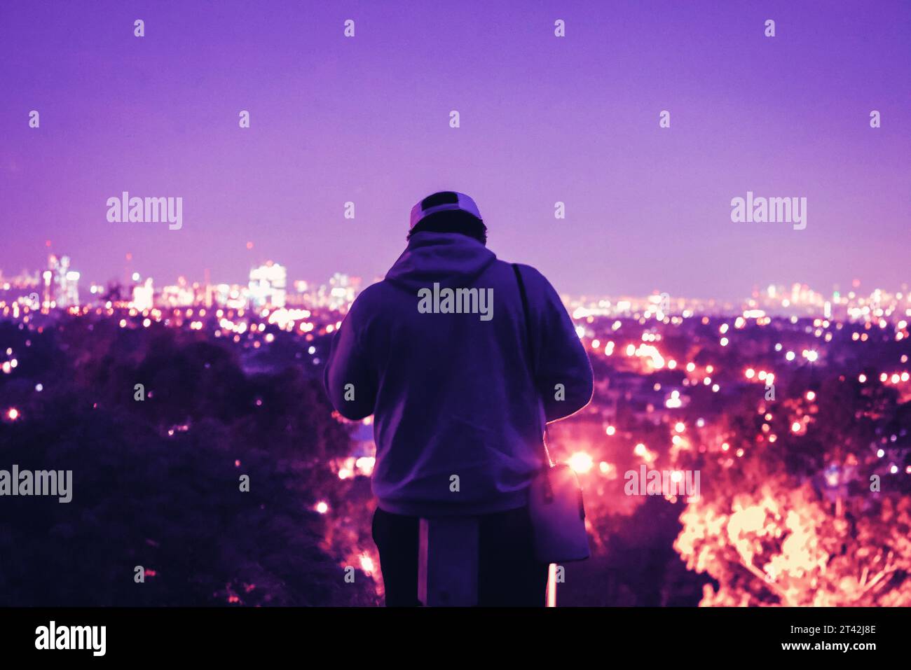 A lone individual stands on the peak of a mountain, gazing out at the ...