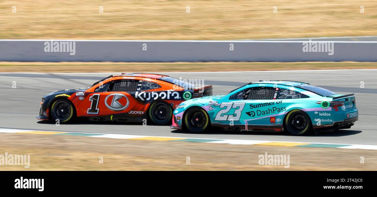 A vibrant race car whizzes past another car on the track, boasting a ...