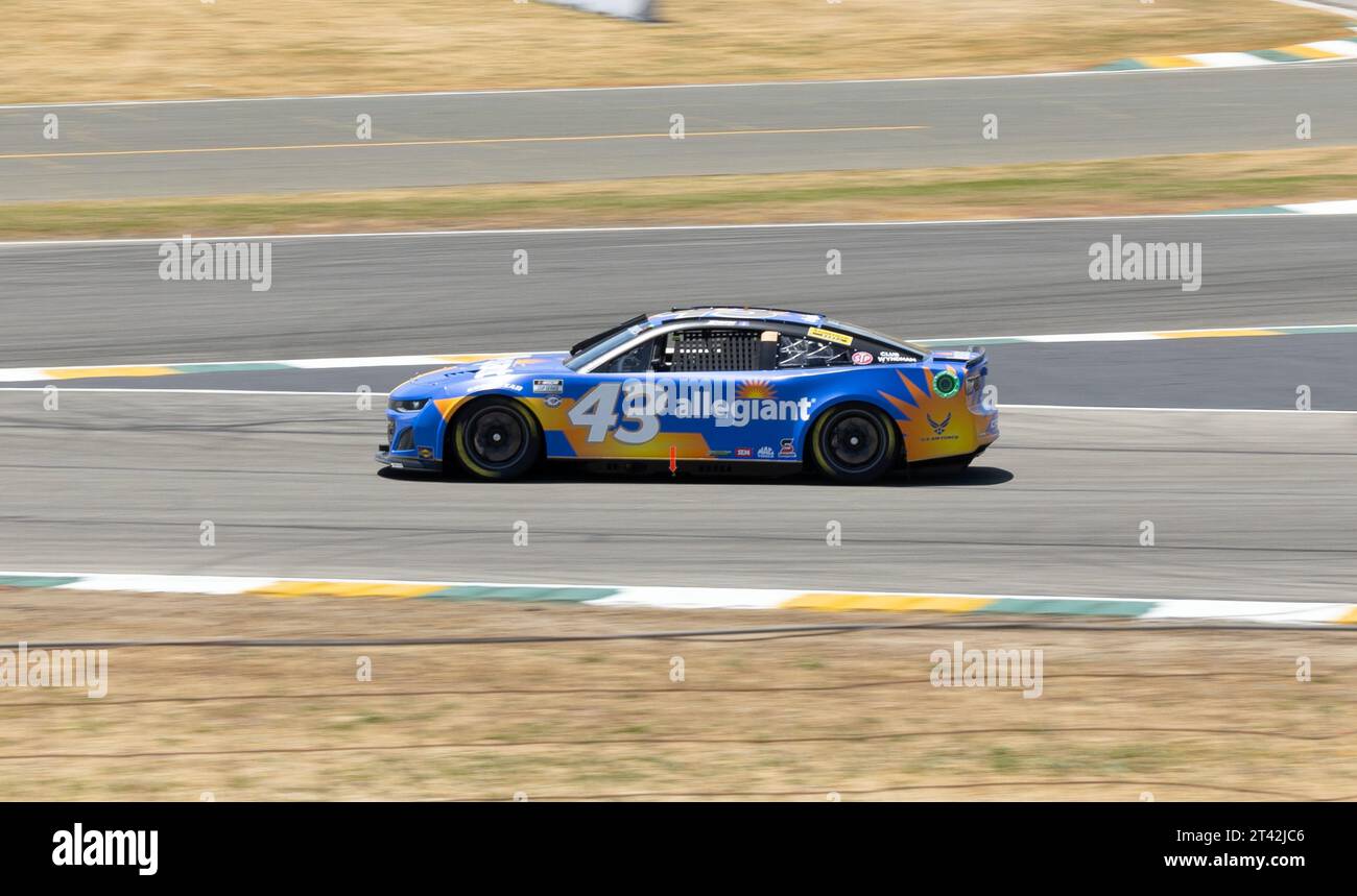 A male driver in a blue and white race car zooming around a track ...