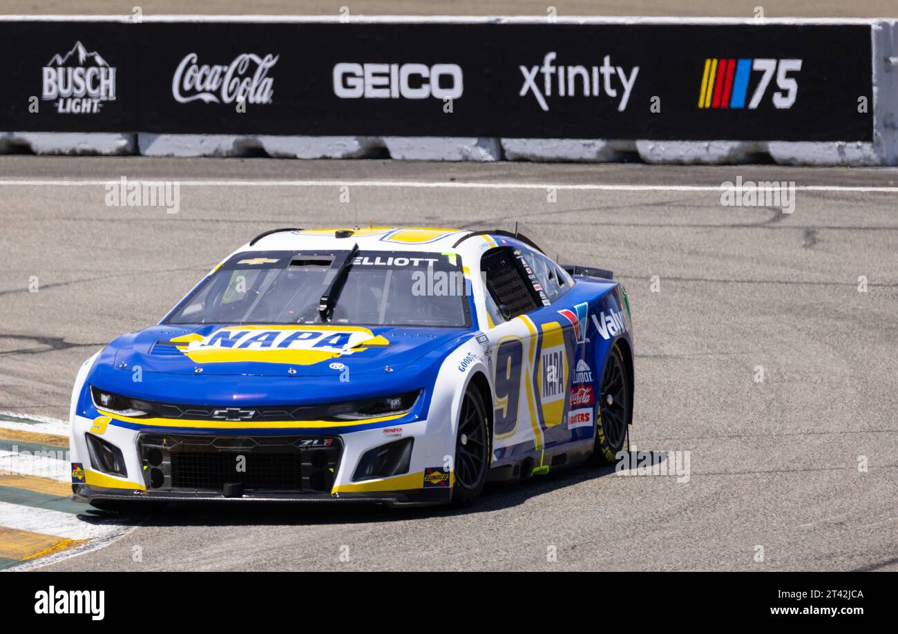 A vibrant red racing car is taking a sharp turn on a racetrack, with a crowd of spectators ...