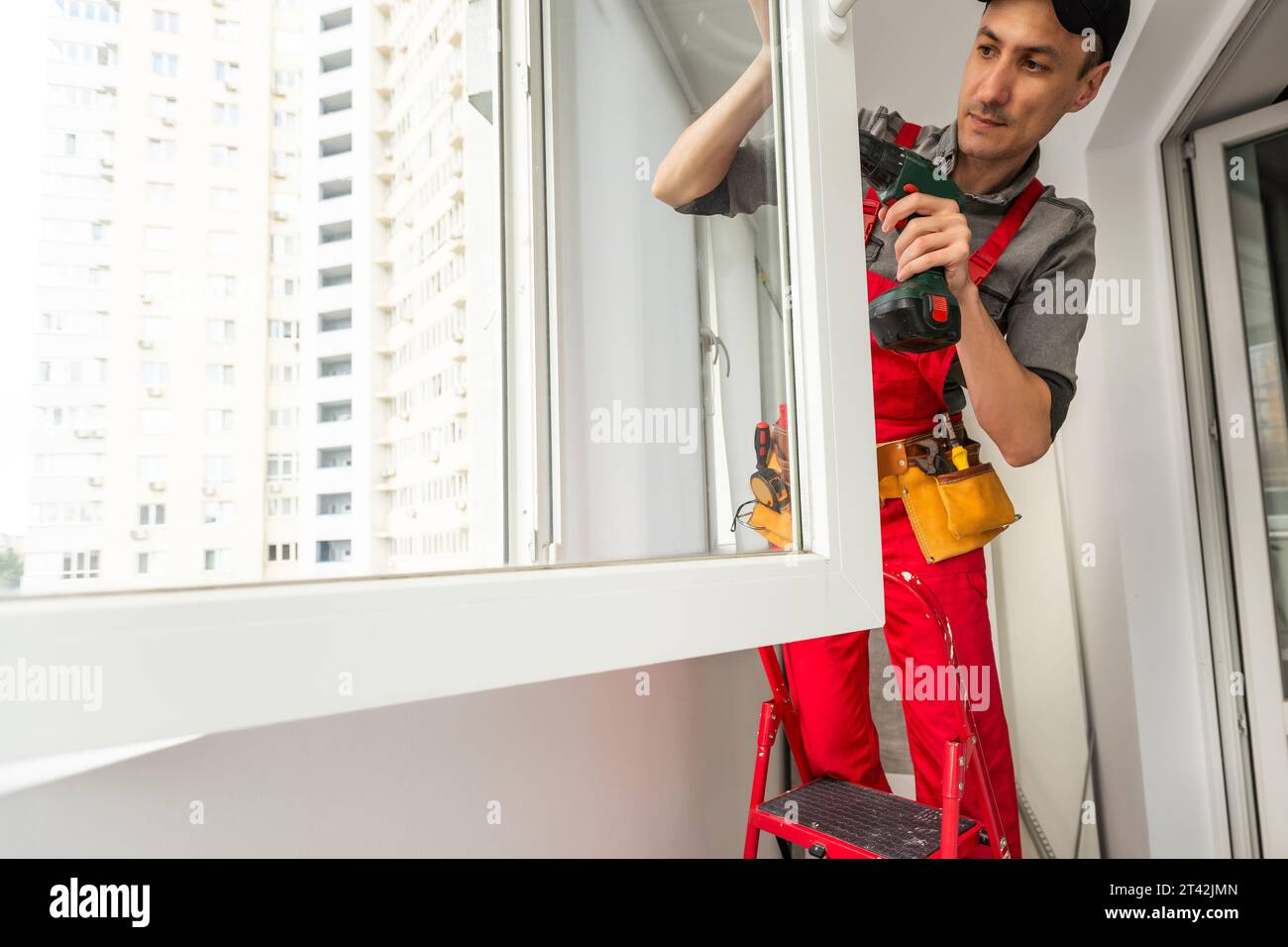 Construction worker repairing plastic window with electric screwdriver ...