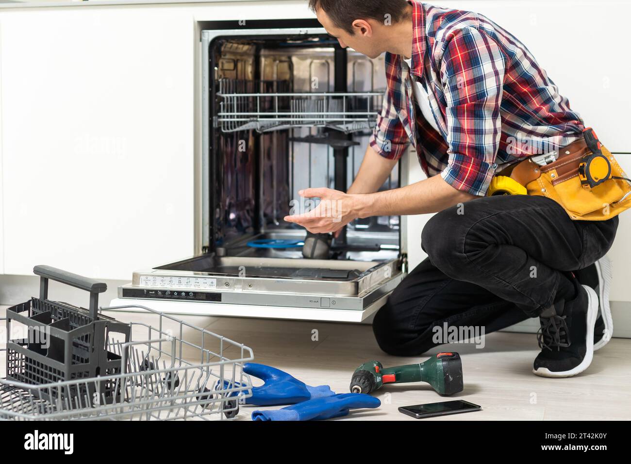 Man repairing a dishwasher with tools Stock Photo - Alamy