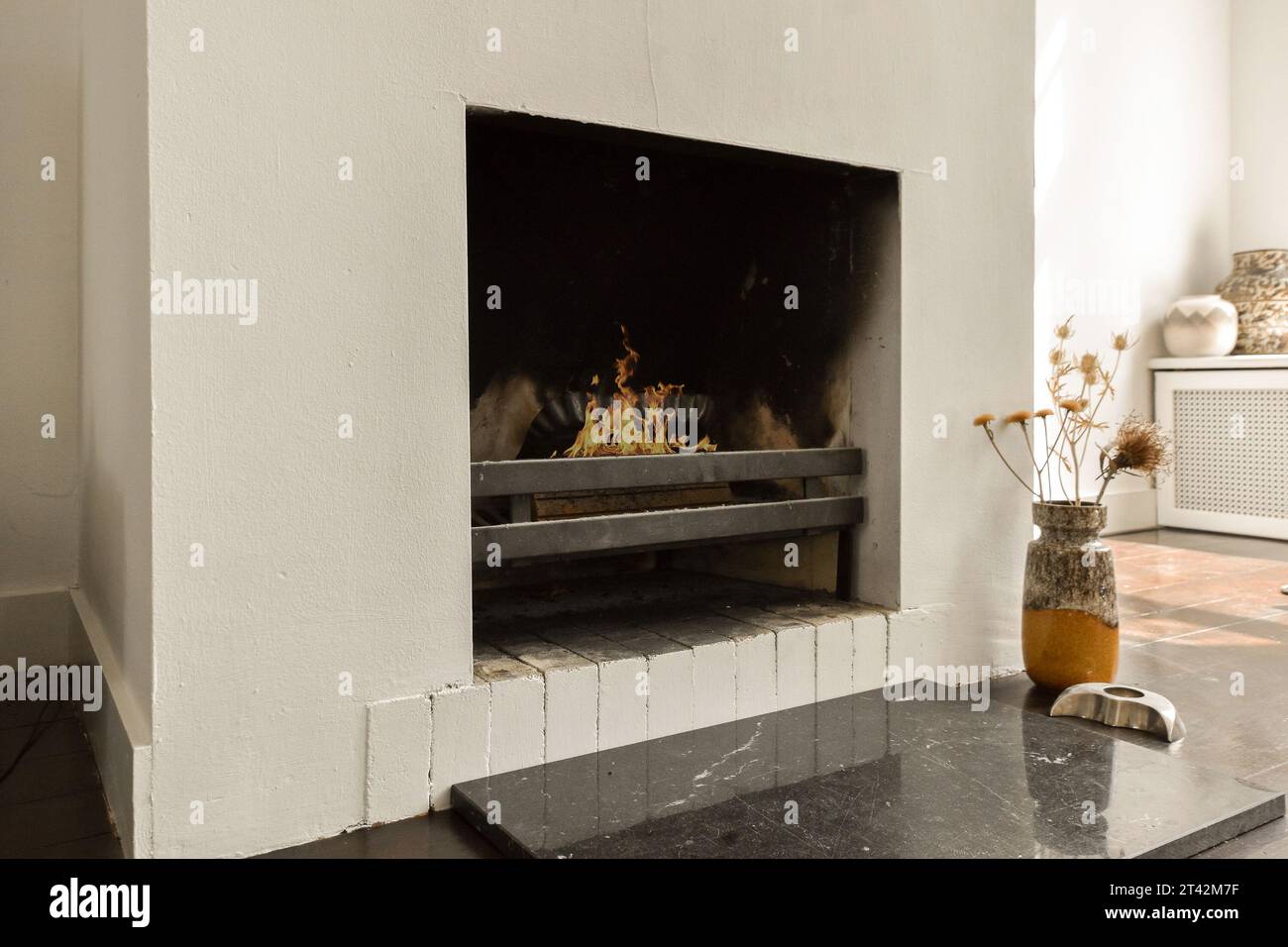 a fireplace in a room with white walls and black tiles on the floor ...