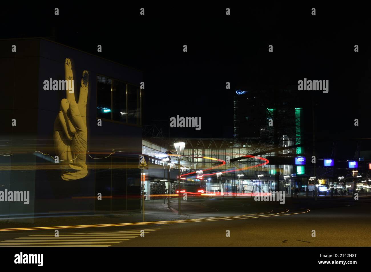 This image captures a bustling city street at night, illuminated by the ...