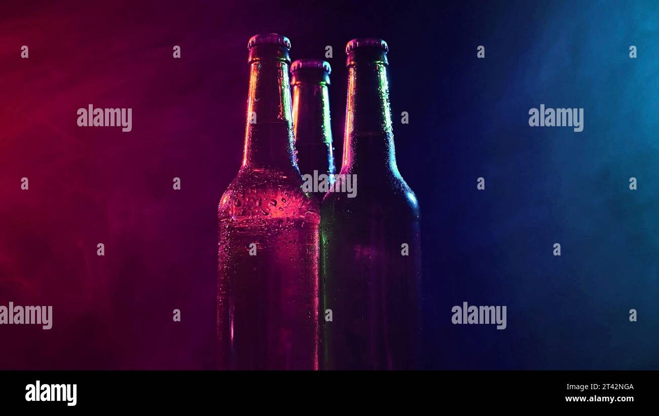 Three bottles of beer spinning in a blue-pink mist Stock Photo - Alamy