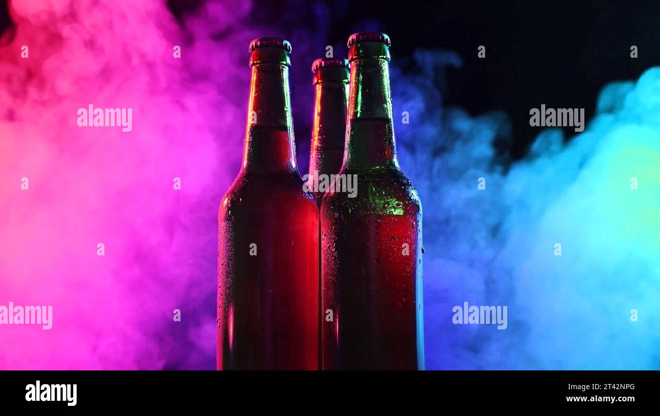 Three bottles of beer spinning in blue pink fog Stock Photo - Alamy