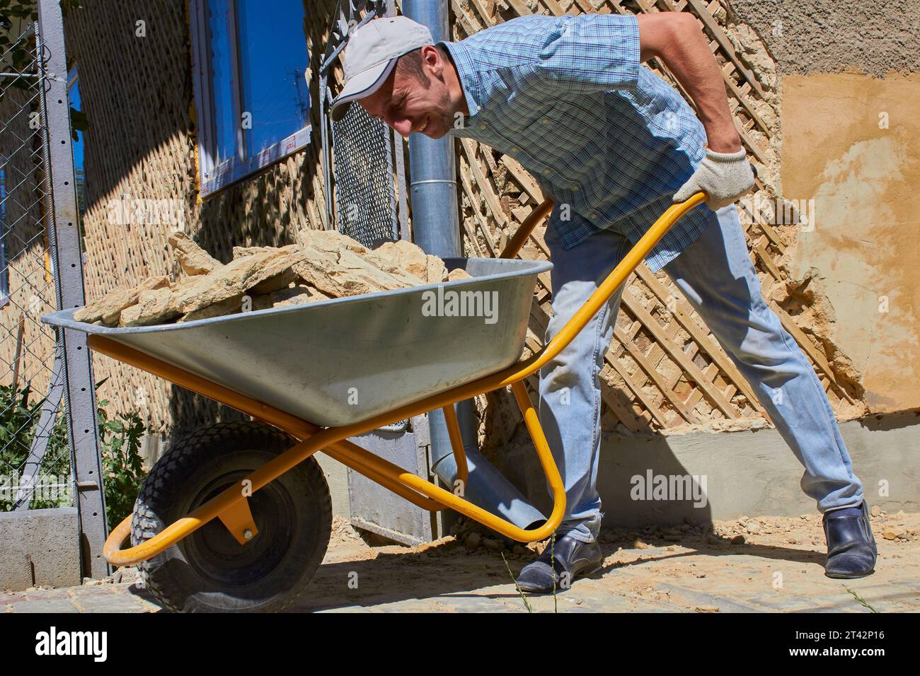 man pushes a full wheelbarrow of construction debris Stock Photo - Alamy