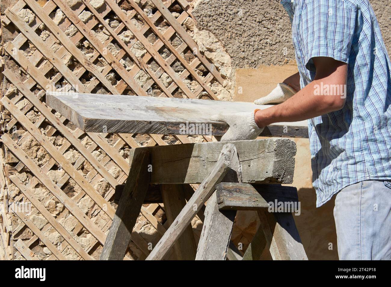 hands of builder lay board on ancient scaffolding near wall of house ...