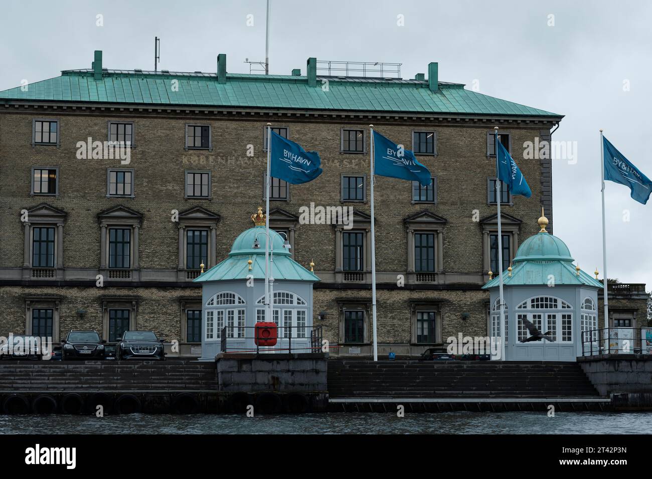 Three national flags waving in the breeze atop a tall building near a ...