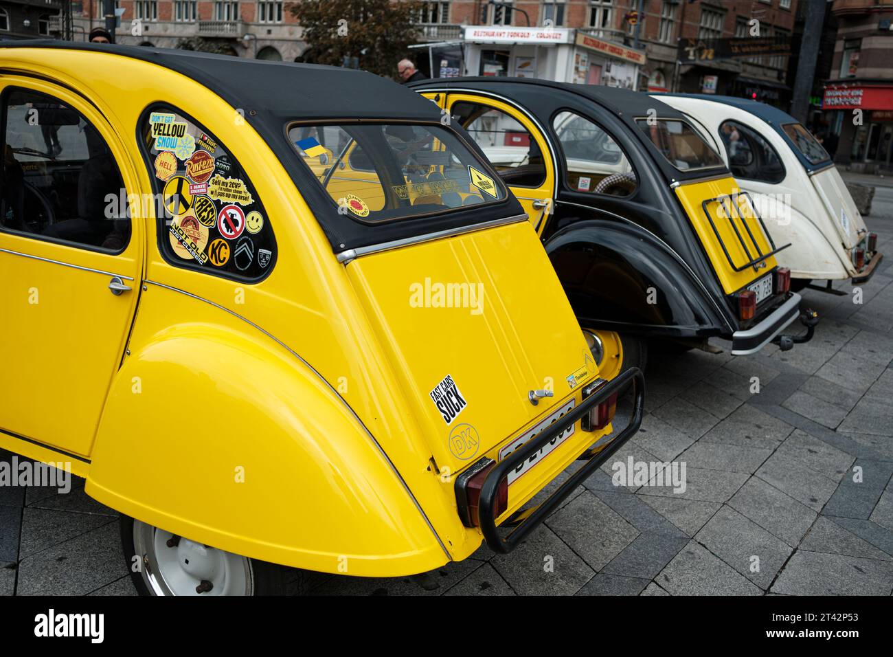 Three vintage yellow cars parked side by side, with a street sign in ...
