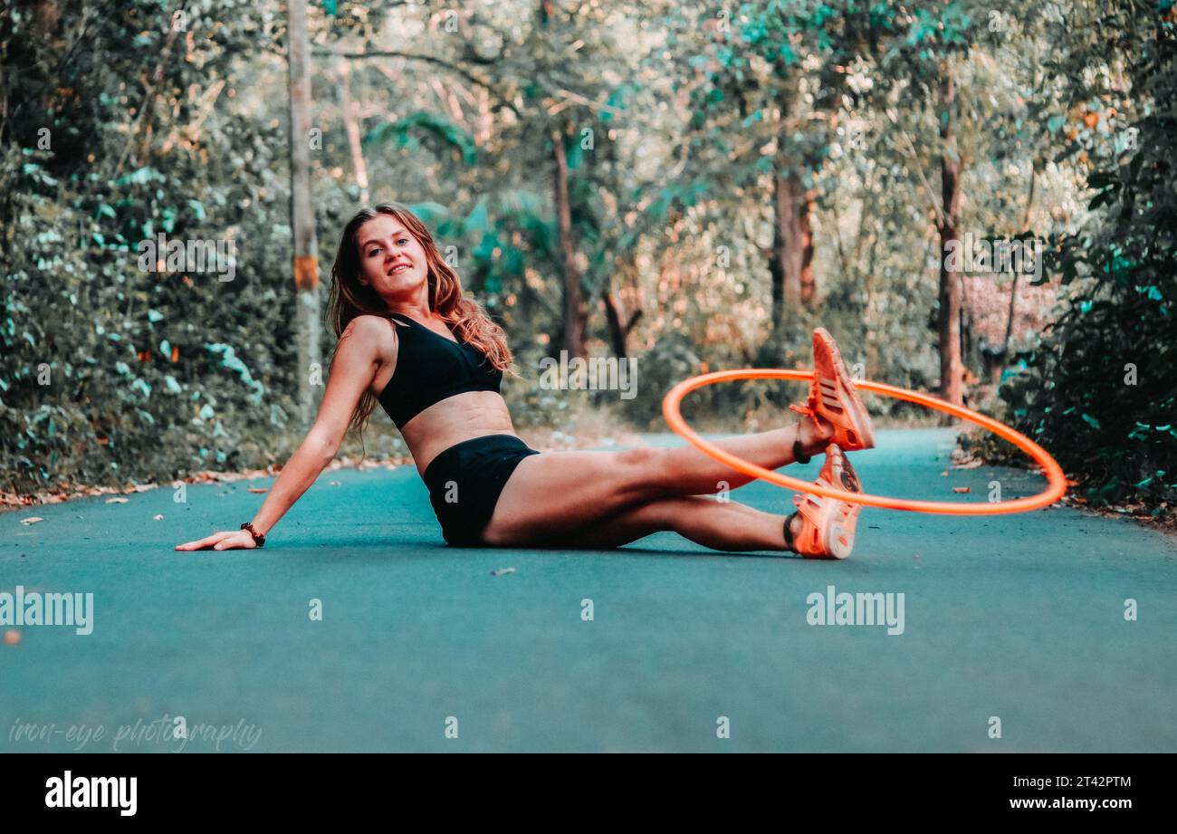 A young girl with long brown hair stands in a grassy field, her arms held out in a pose as she ...