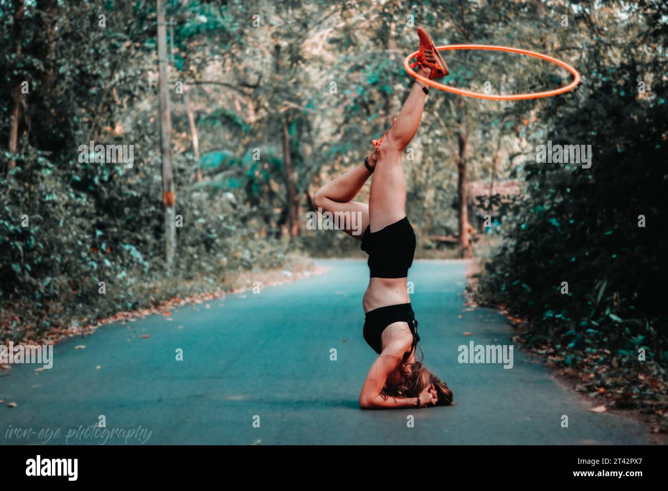 A young woman performing an acrobatic maneuver with a hula hoop on a ...