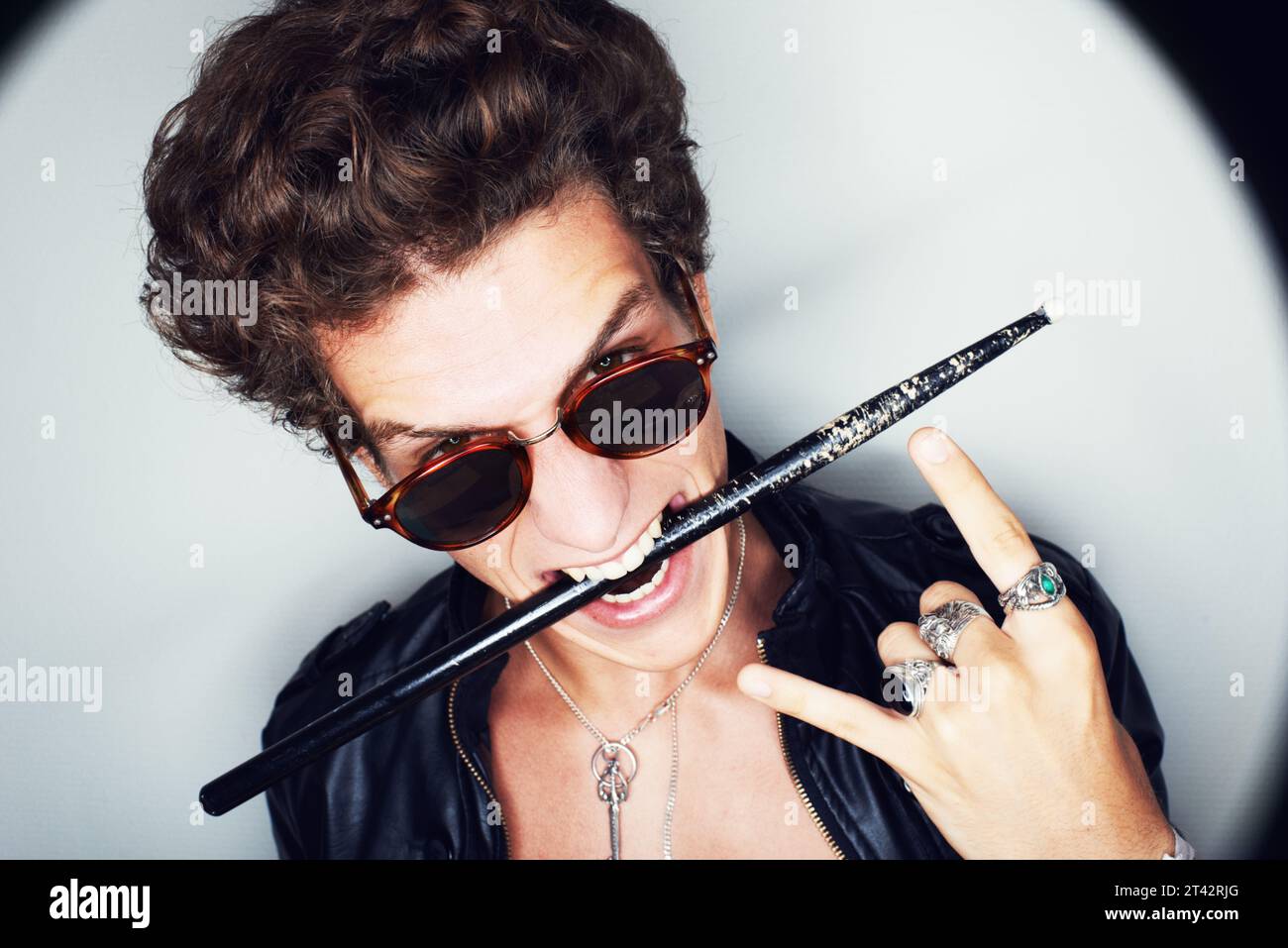 Rock man, horns and studio portrait with drumstick, sunglasses or ...