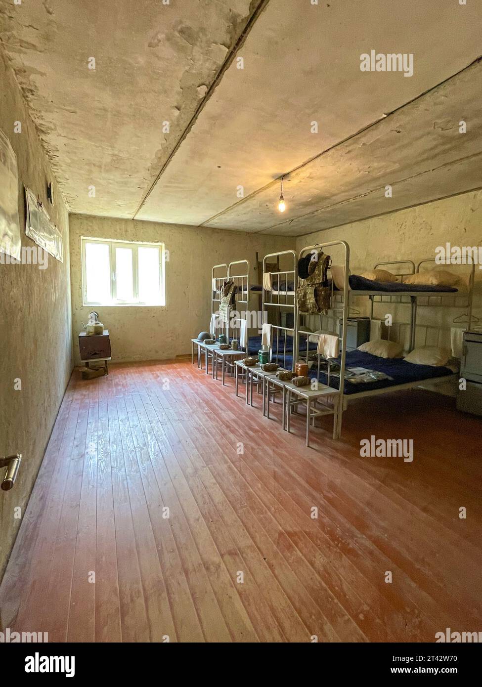 Sleeping quarters with rows of metal bunk beds and various uniform ...
