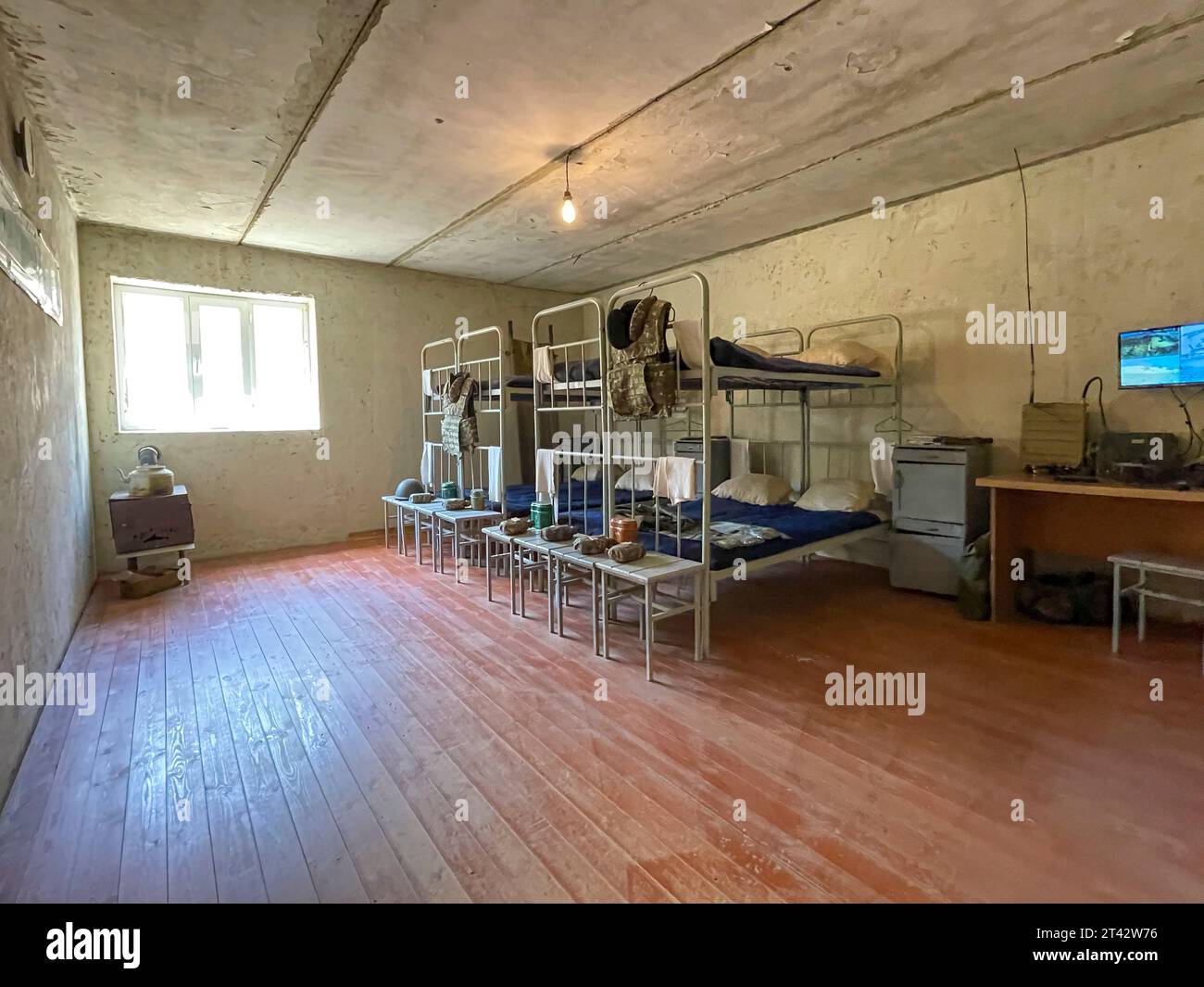 Sleeping quarters with rows of metal bunk beds and various uniform ...