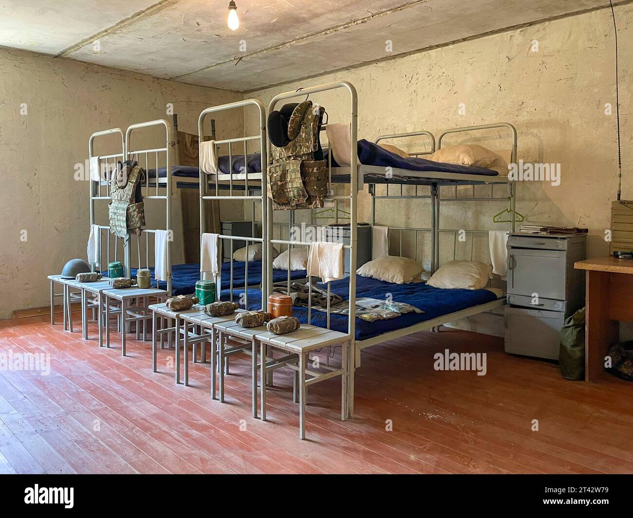 Sleeping quarters with rows of metal bunk beds and various uniform ...