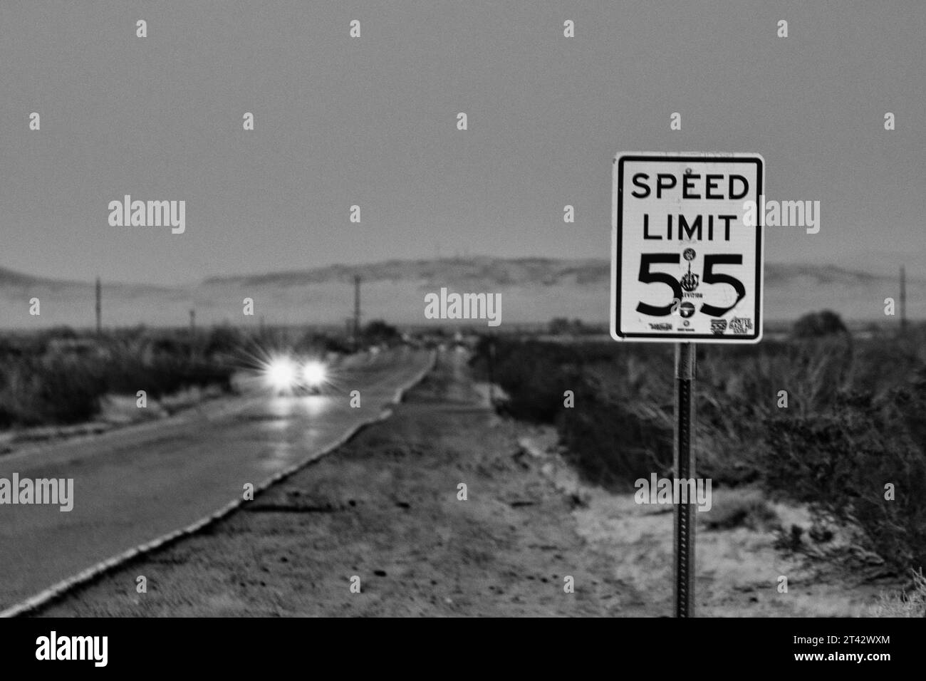 A vintage speed limit sign standing in the desert at dusk with a ...