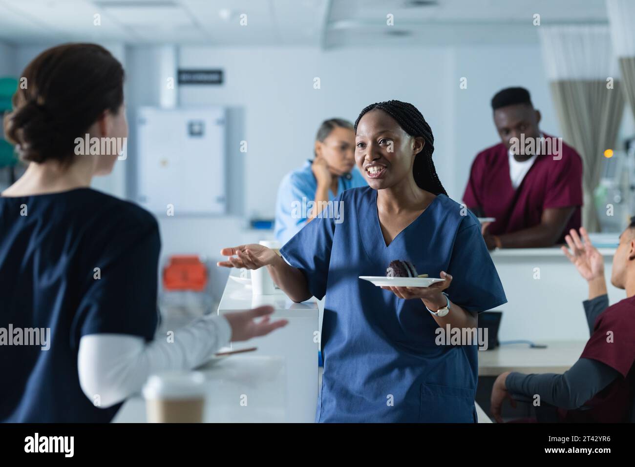 Happy diverse male and female doctors eating birthday cake at reception ...