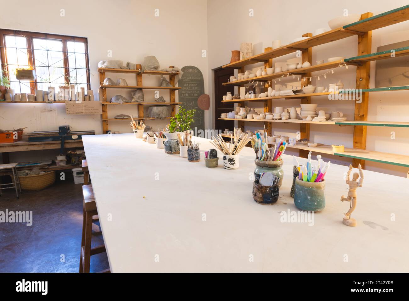 Pottery tools on table and pottery on shelves in pottery studio Stock ...