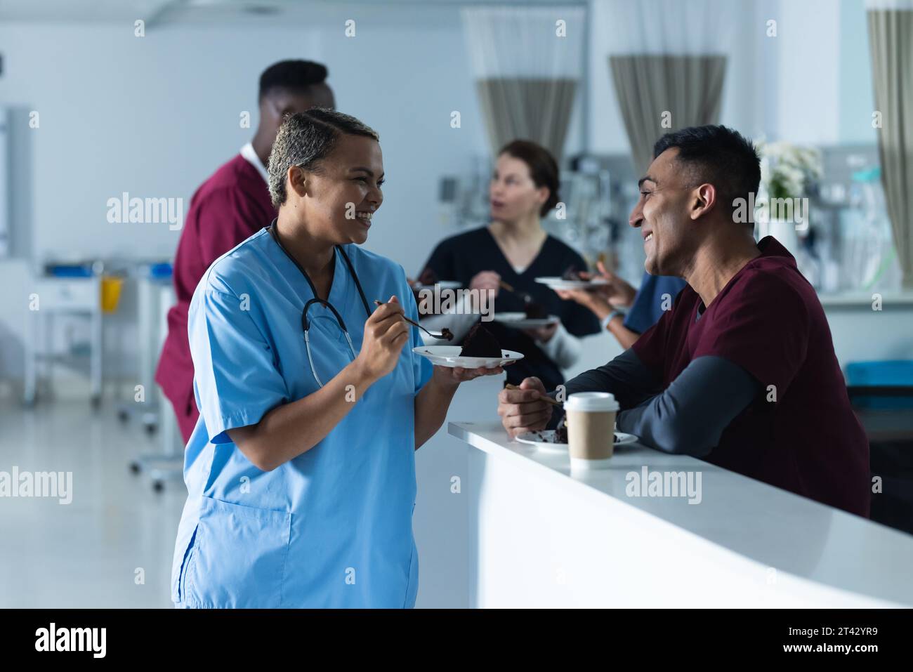 Happy diverse male and female doctors eating birthday cake at reception ...