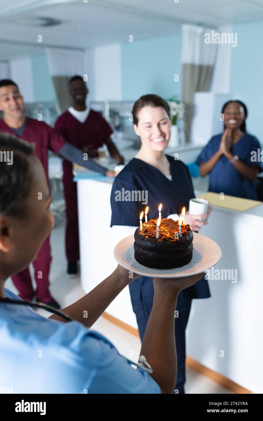 Happy diverse male and female doctors celebrating birthday at reception ...