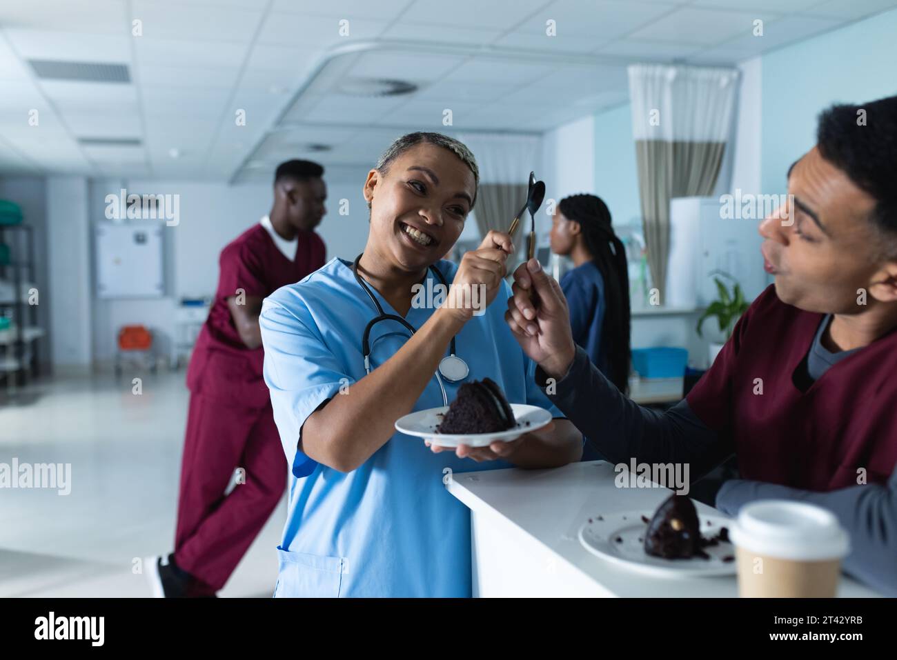 Happy diverse male and female doctors eating birthday cake at reception ...