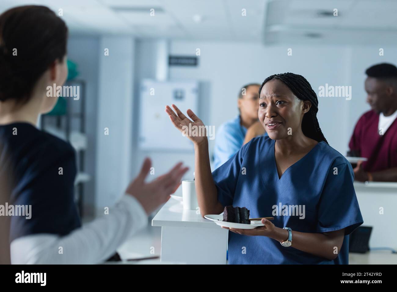 Happy diverse male and female doctors eating birthday cake at reception ...