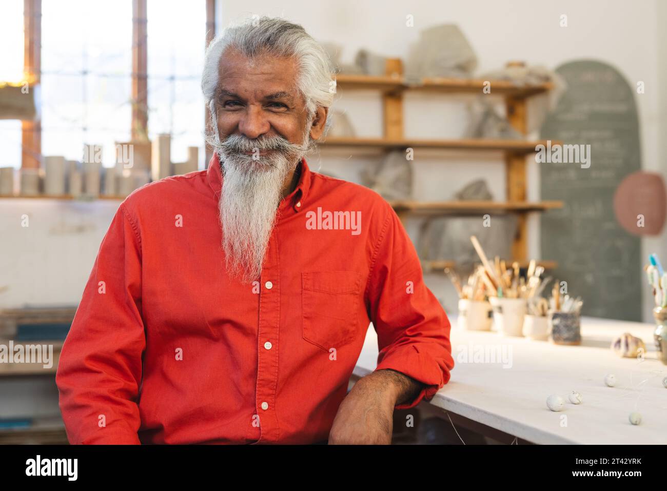 Happy biracial senior man with long beard sitting and smiling in ...